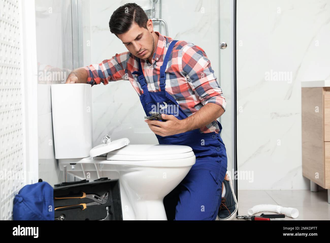 Professional plumber working with toilet bowl in bathroom Stock Photo ...