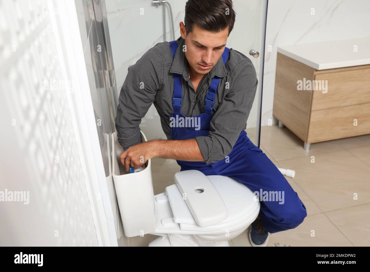 Professional plumber working with toilet bowl in bathroom Stock Photo ...