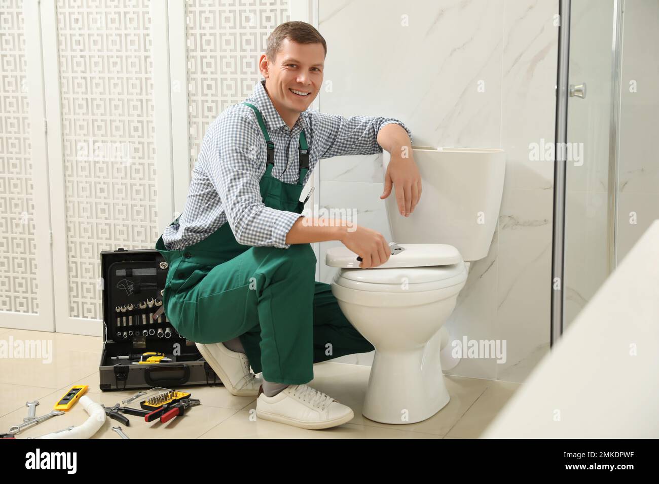 Professional plumber repairing toilet bowl in bathroom Stock Photo - Alamy