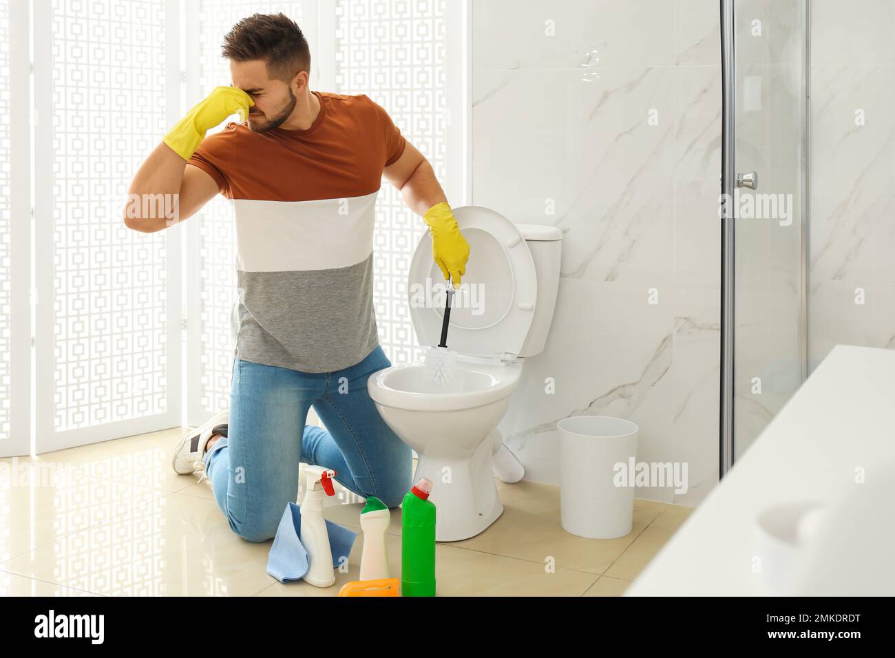 Young man feeling disgust while cleaning toilet bowl in bathroom Stock ...