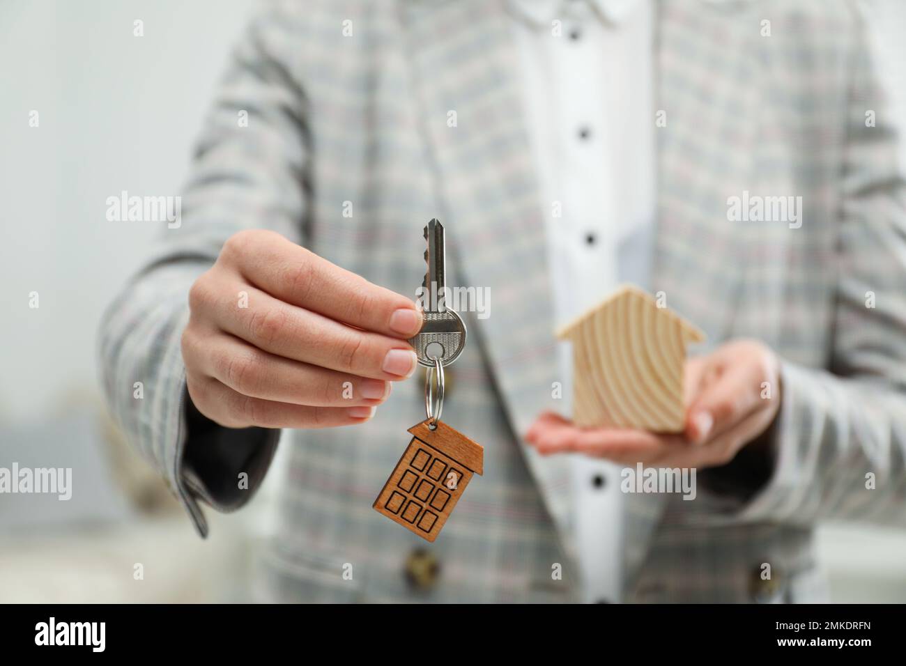 Real estate agent holding house figure and key indoors, closeup Stock ...