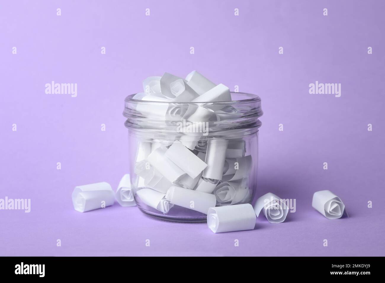 Glass jar full of rolled paper sheets on violet background Stock Photo ...