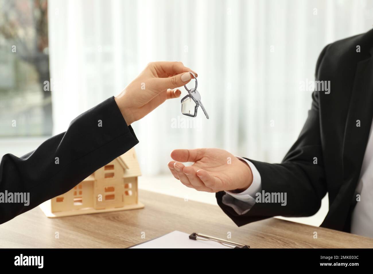 Real estate agent giving key to client at table in office, closeup ...