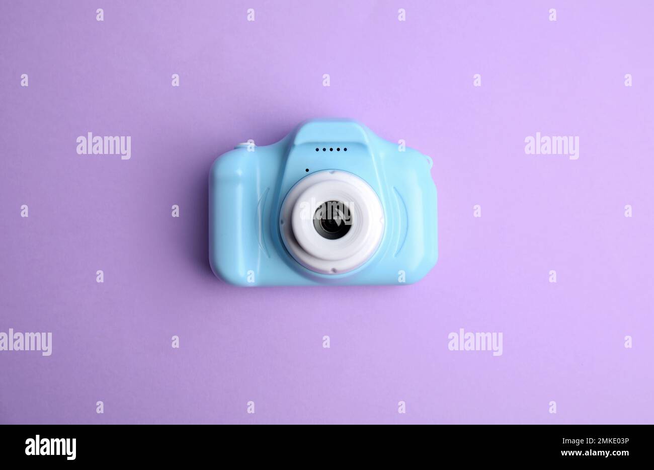 Light blue toy camera on violet background, top view. Future ...