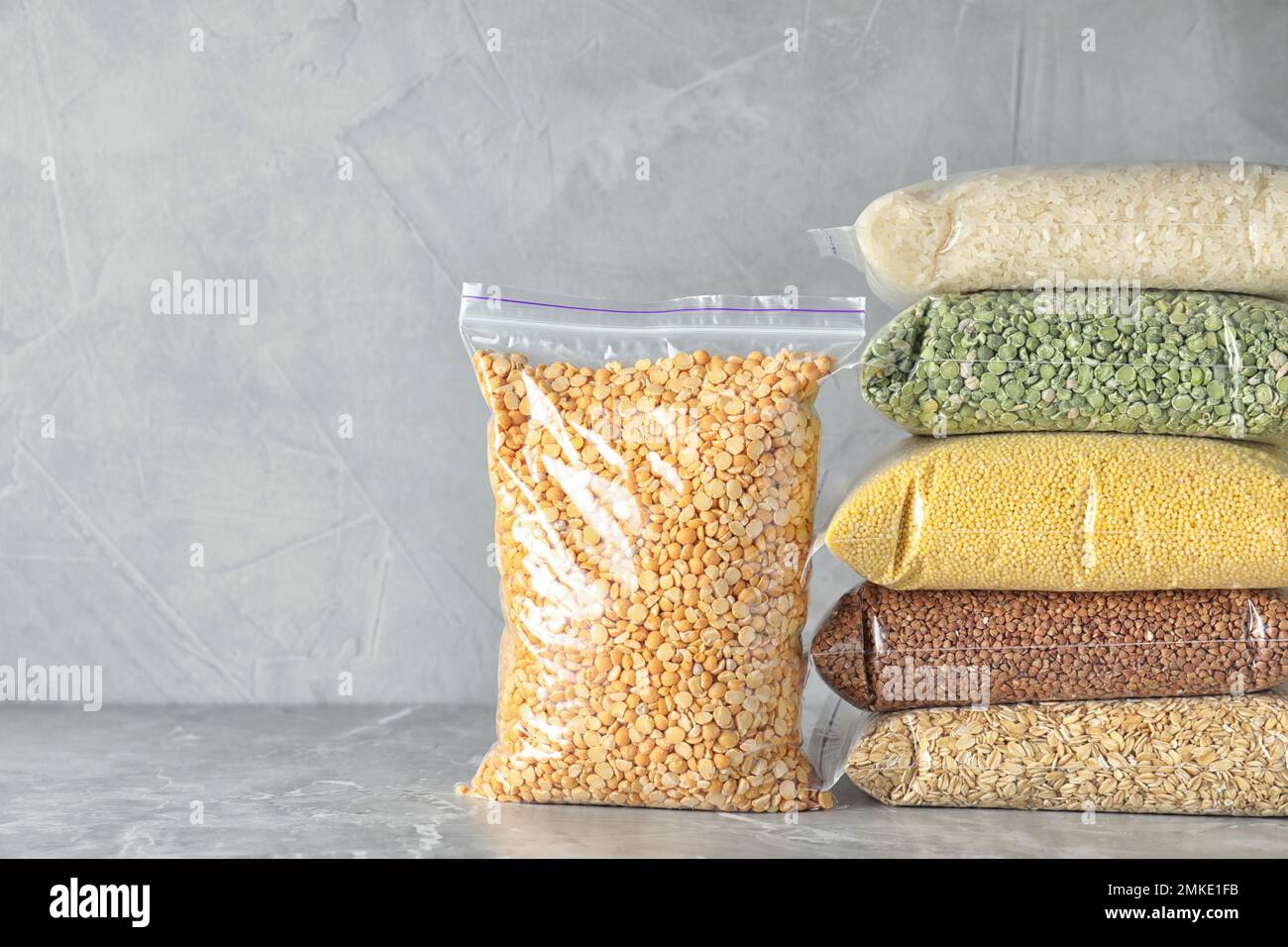 Different types of legumes and cereals on grey marble table, space for ...