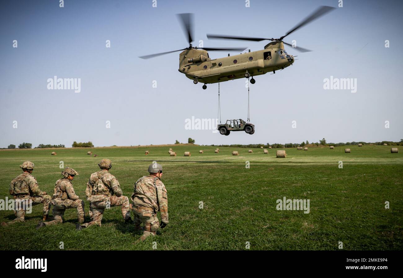 U.S. Soldiers observe as a CH-47 Chinook helicopter sling loads a military vehicle during a U.S ...