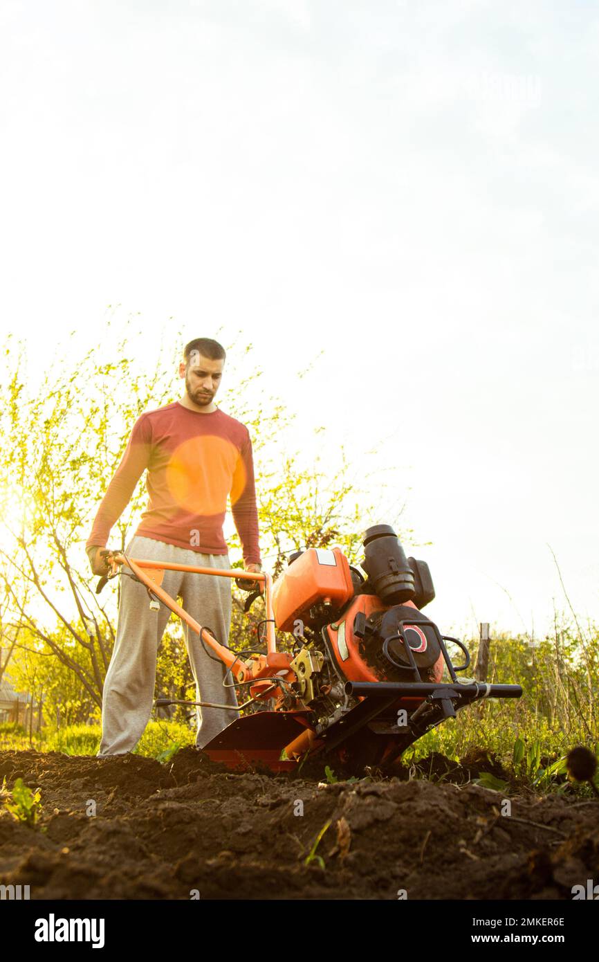A farmer man works in the field, plowing the land with a plow on the ...