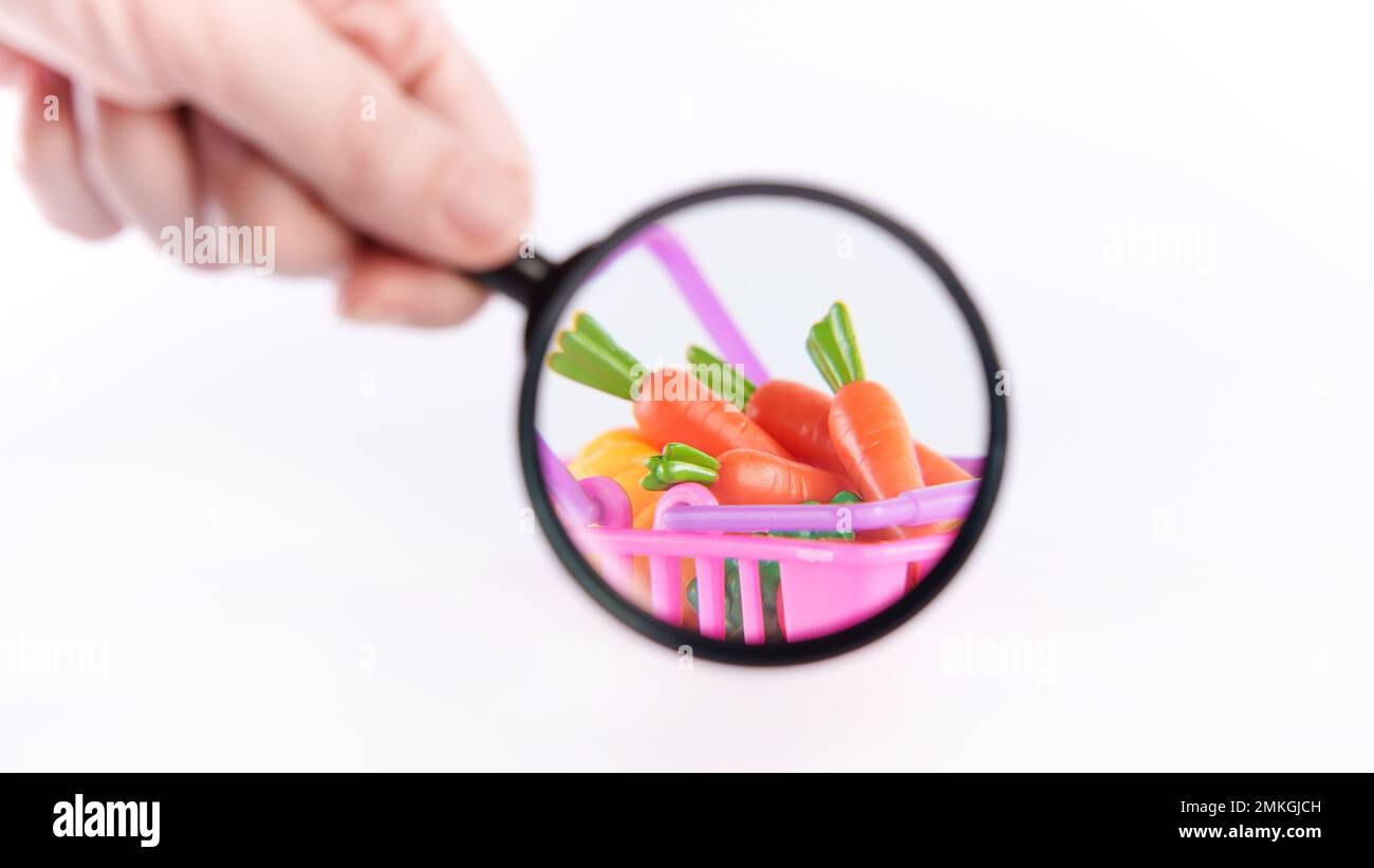 View through magnifying glass on plastic vegetables in shopping basket ...