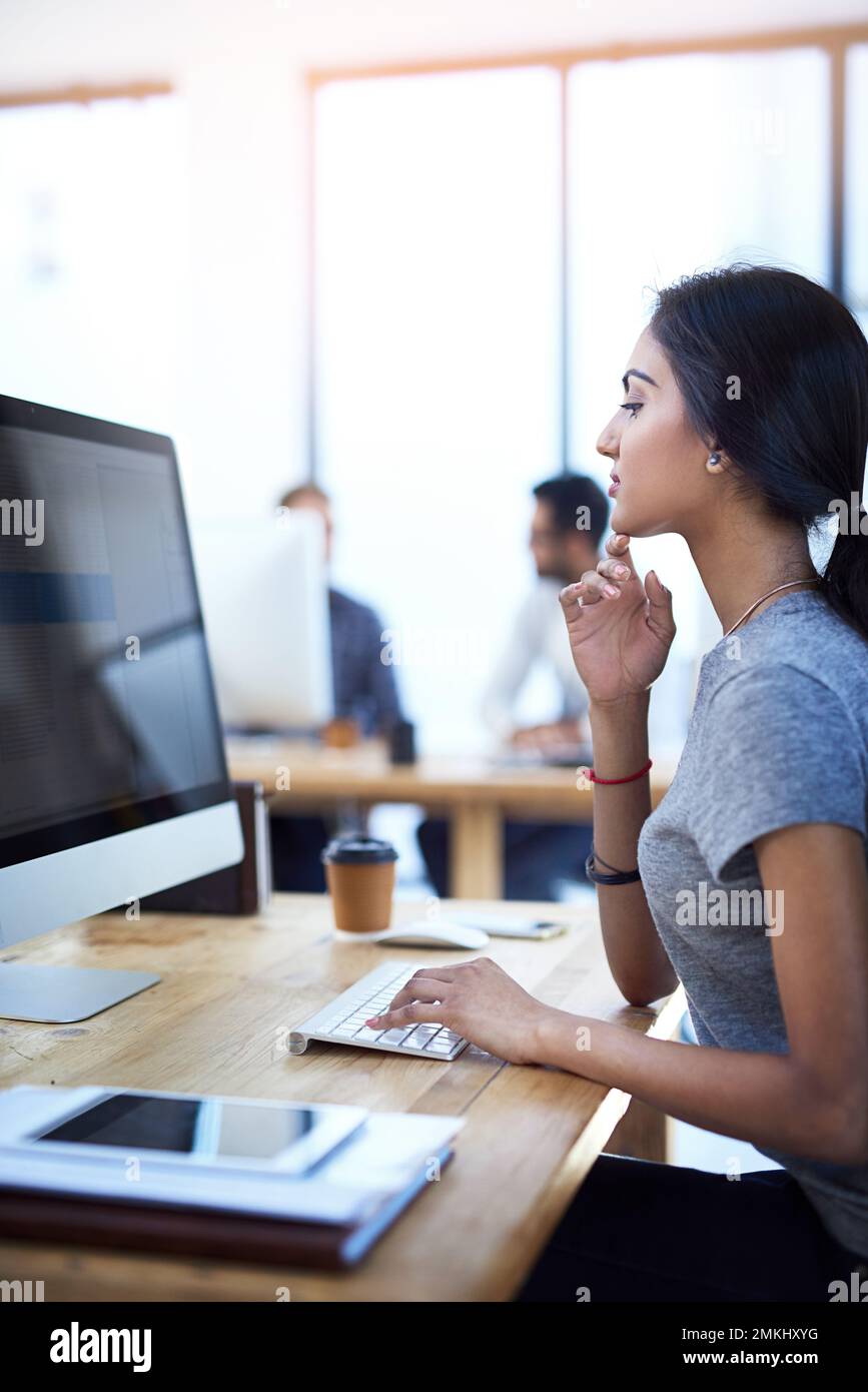 Absorbed in her work tasks. a focused young businesswoman using a ...