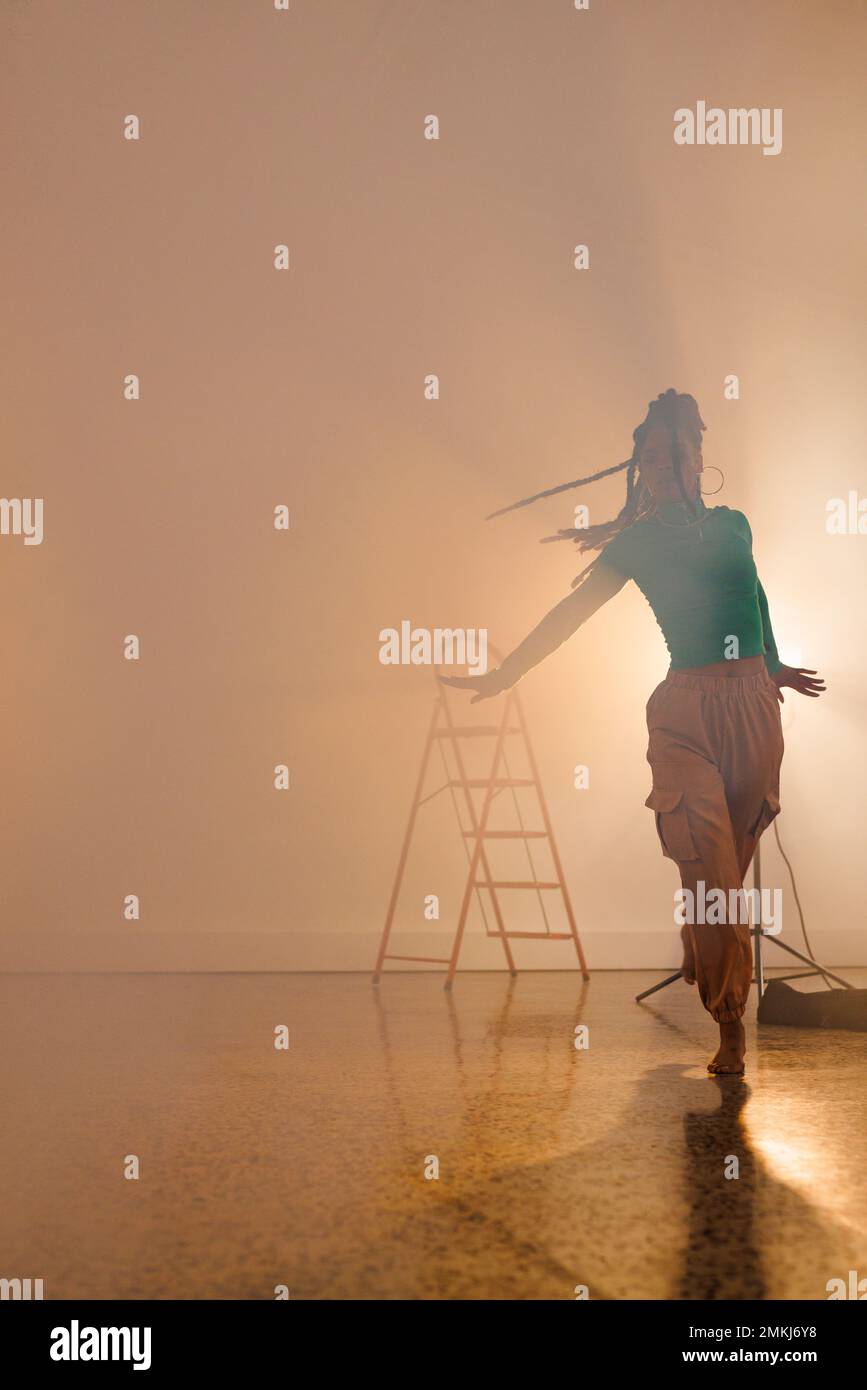 Vertical image of biracial female modern dancer dancing in smoked ...