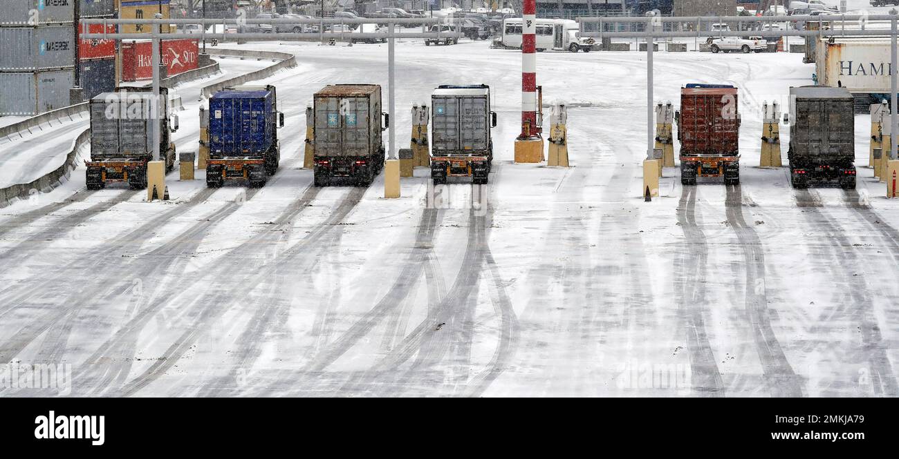 Trucks hauling shipping containers leave tracks as they make their way ...