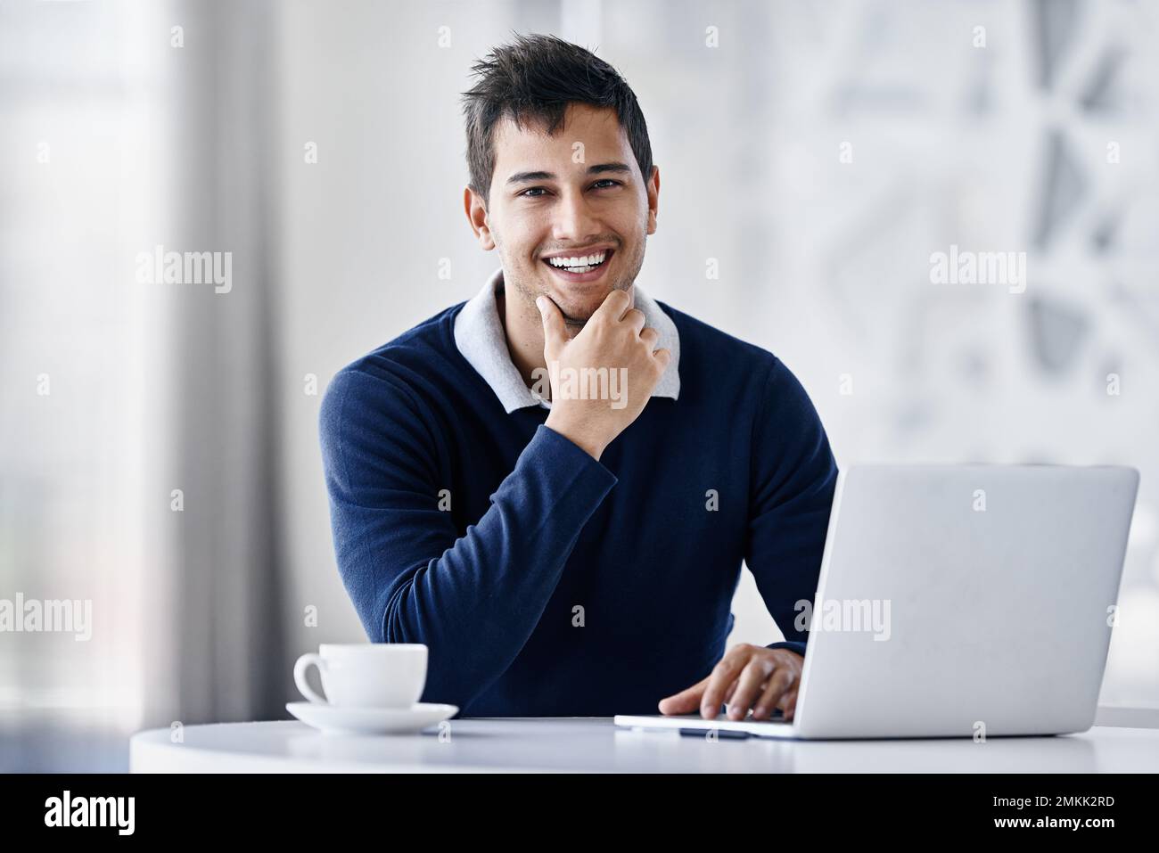 Finding satisfaction in a job well done. Portrait of a smiling young businessman using a laptop ...