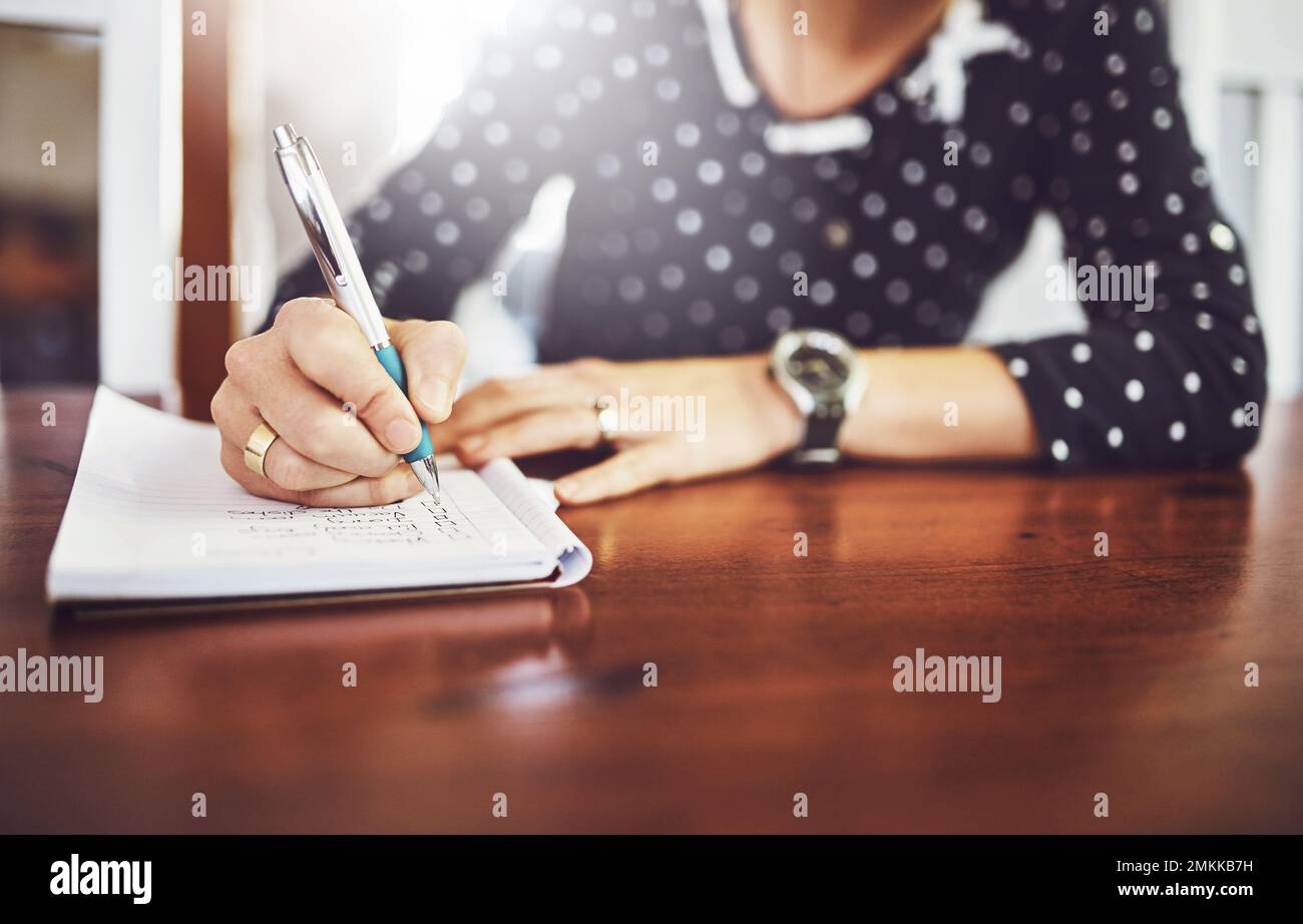 Making daily notes. a unrecognizable woman writing in a book with a pen ...