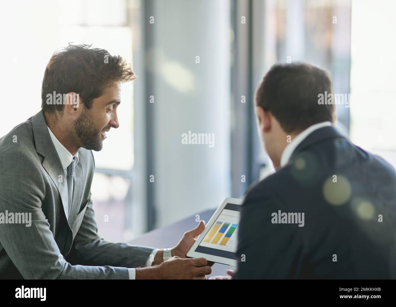 These numbers are fantastic. two colleagues looking at a graph on a ...