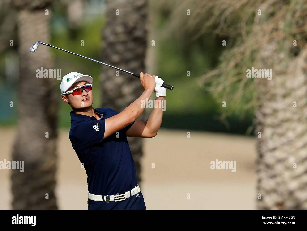 Haotong Li of China follows his ball on the 14th hole during round ...