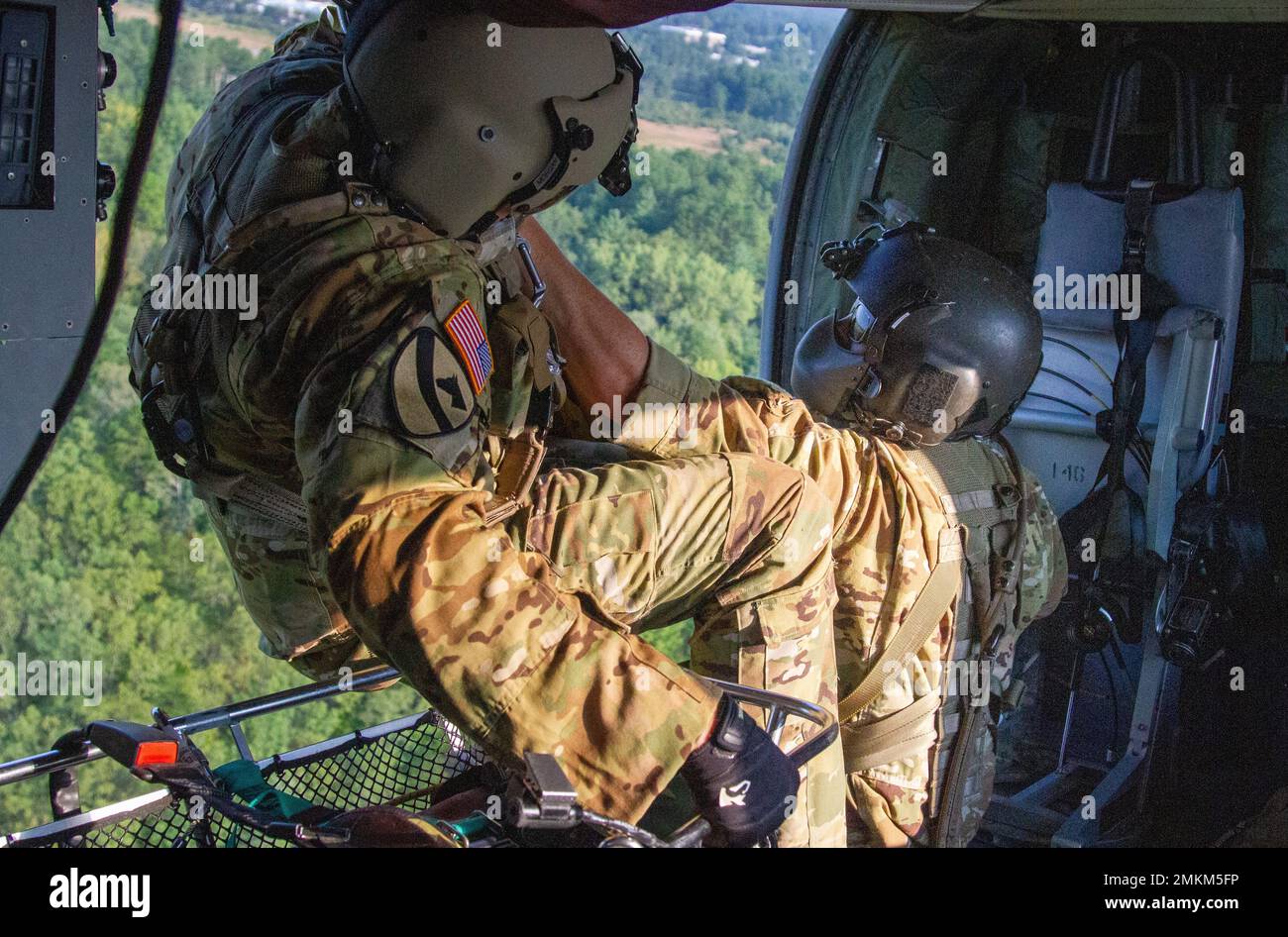 (From right to left) Spc. Nate MacDonald, a crew chief, performs hoist ...