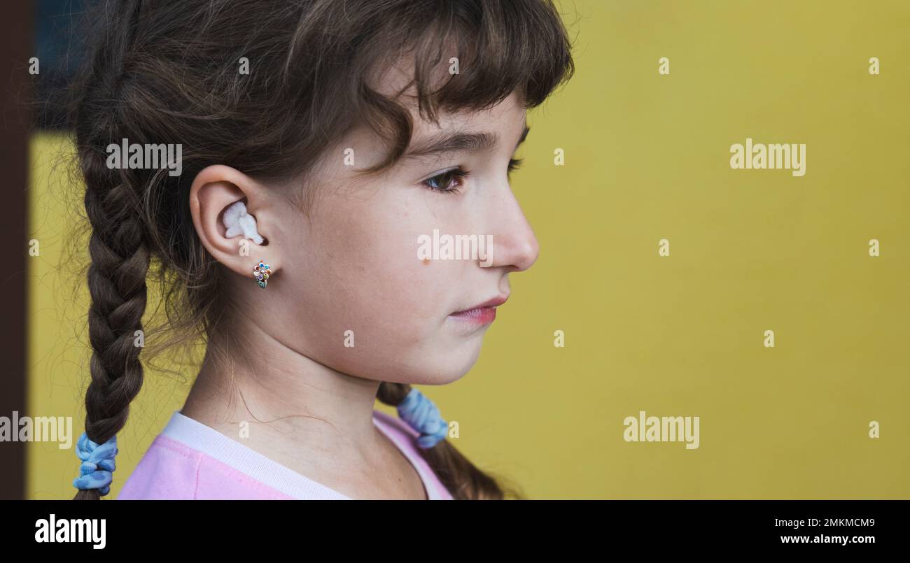 Girl with a warming therapeutic cotton swab in the ear with a sad and ...