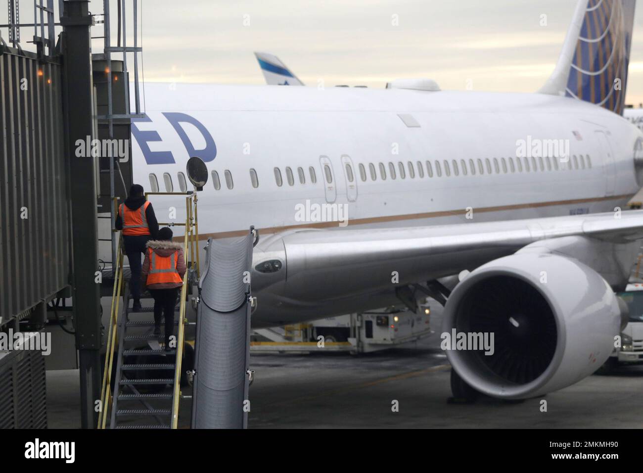Employees walk up a ramp toward a ramp where a United Airlines jet is ...
