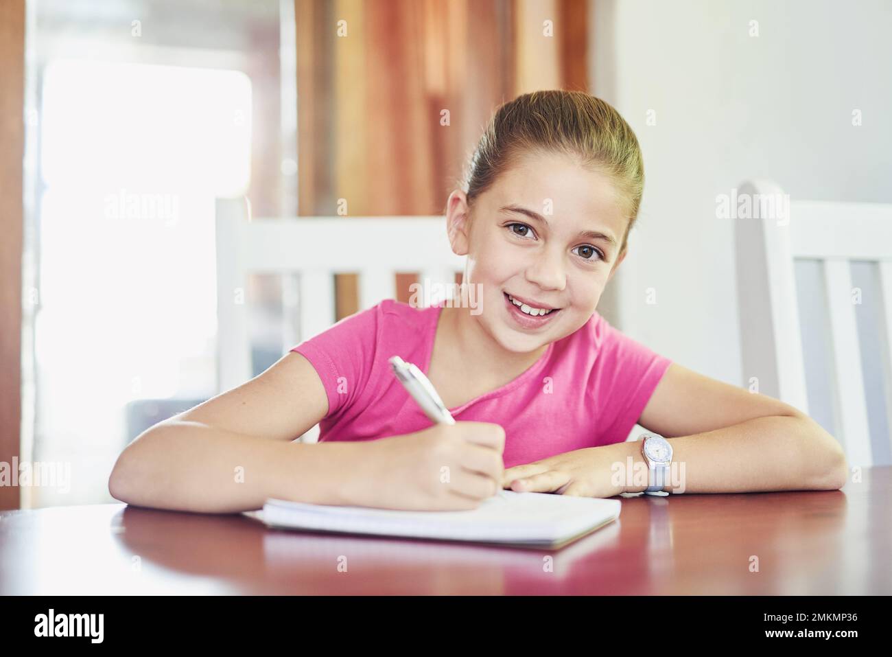 Jotting down some notes. Portrait of a young girl writing in a book at ...