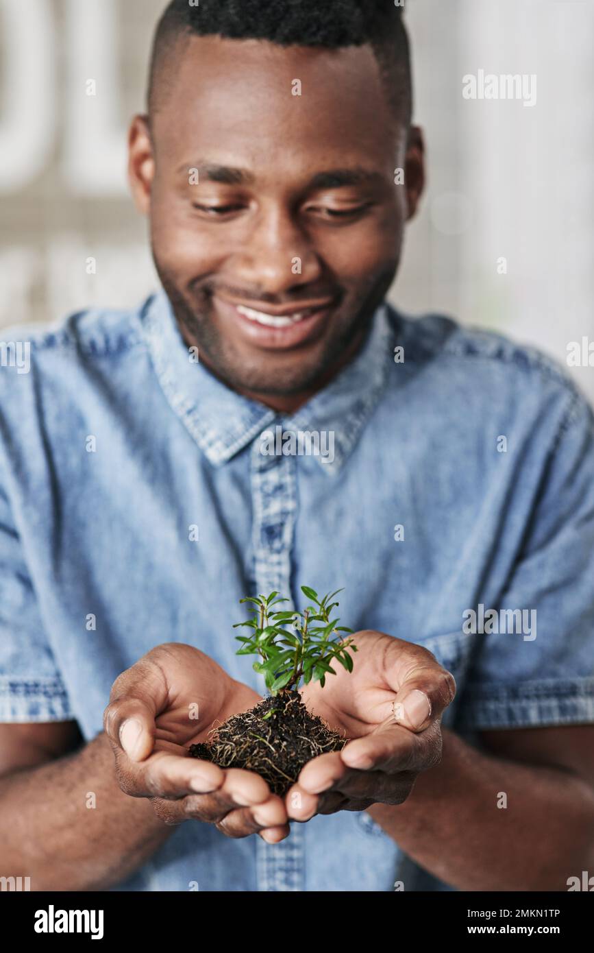 Time to get growing with your new business. a young man holding a plant ...
