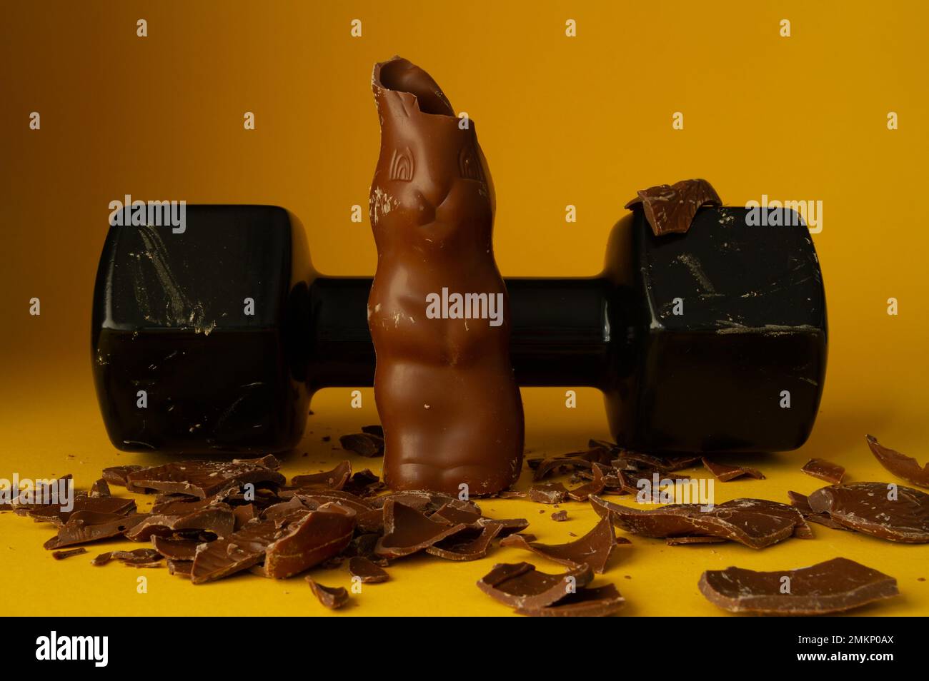 Dumbbell crushing Easter chocolate bunny. Gym workout, fitness exercise ...