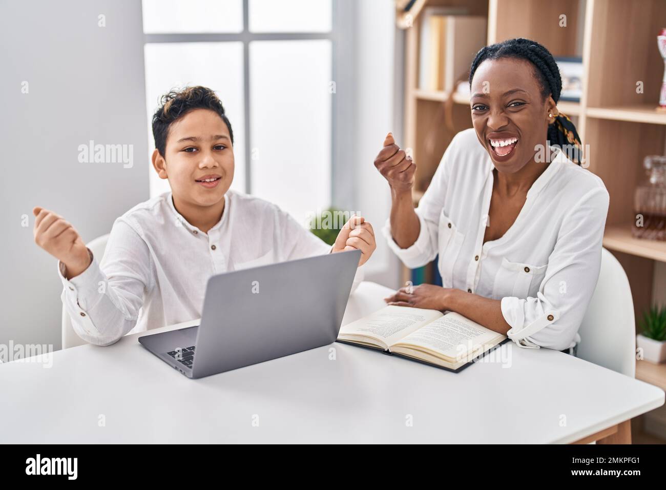 Young mother and son doing homework with laptop screaming proud ...