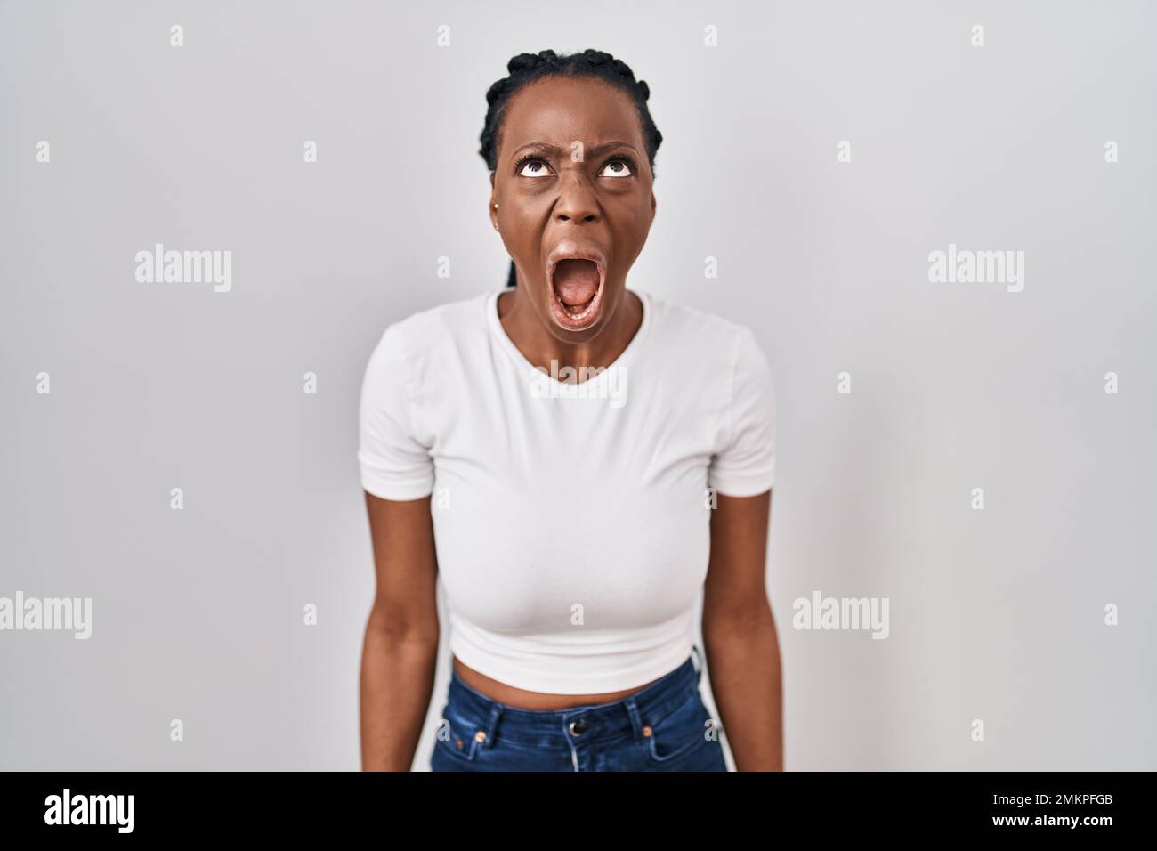 Beautiful black woman standing over isolated background angry and mad ...