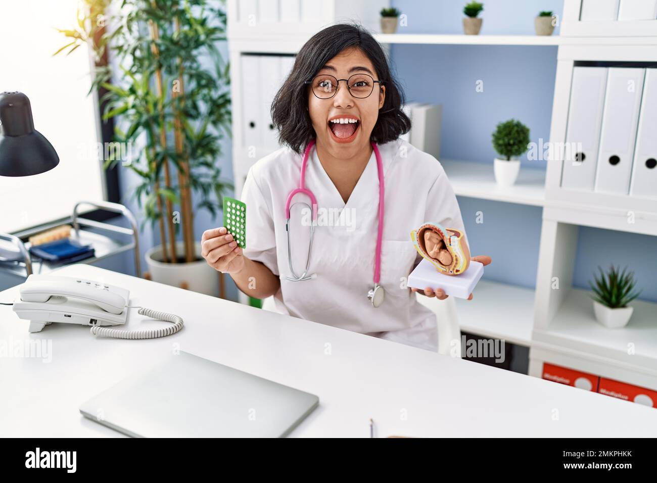 Young hispanic doctor woman holding anatomical model of uterus with ...
