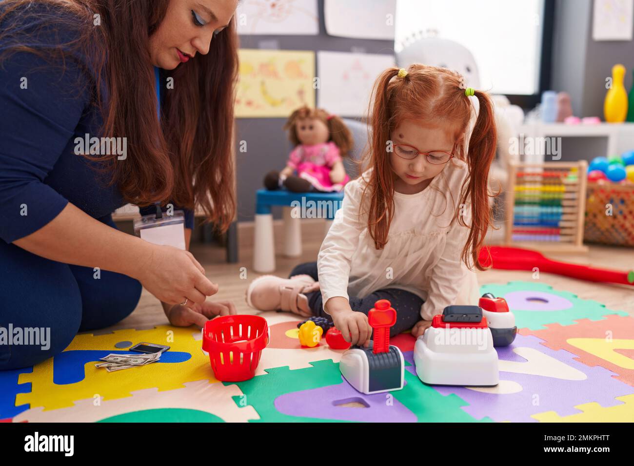Teacher and student playing supermarket game sitting on floor at ...
