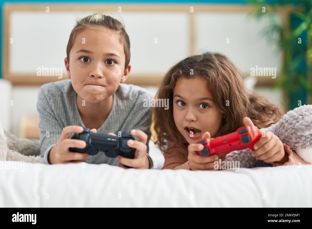 Two kids playing video game lying on bed at bedroom Stock Photo - Alamy