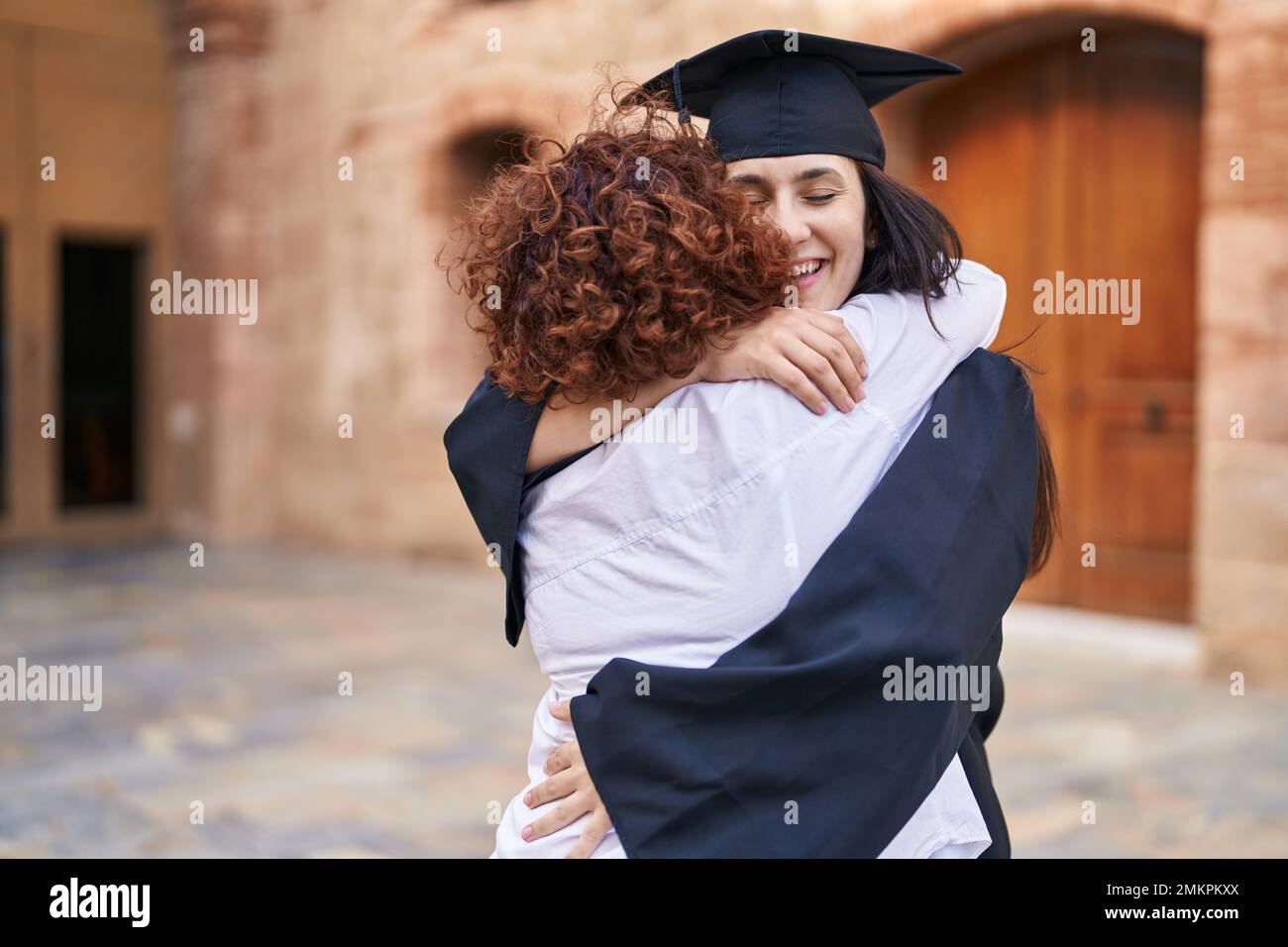 Two women mother and daughter hugging each other celebrating graduation ...