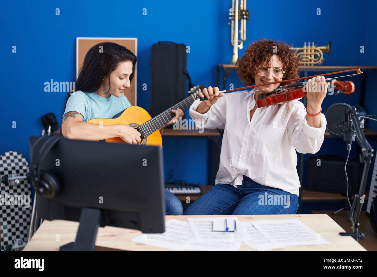 Two women musicians playing classical guitar and violin at music studio ...