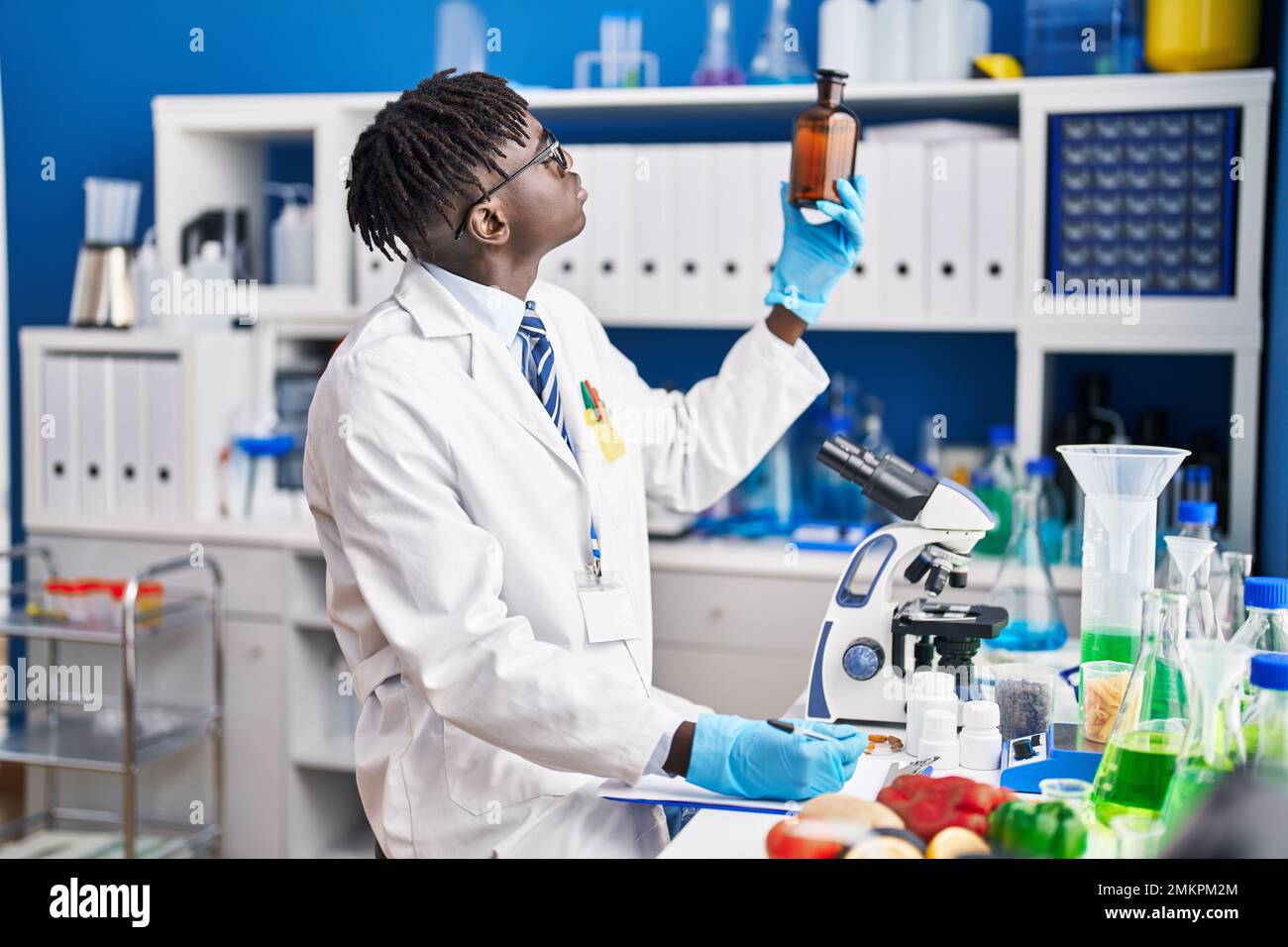 African american man scientist writing report holding bottle at ...