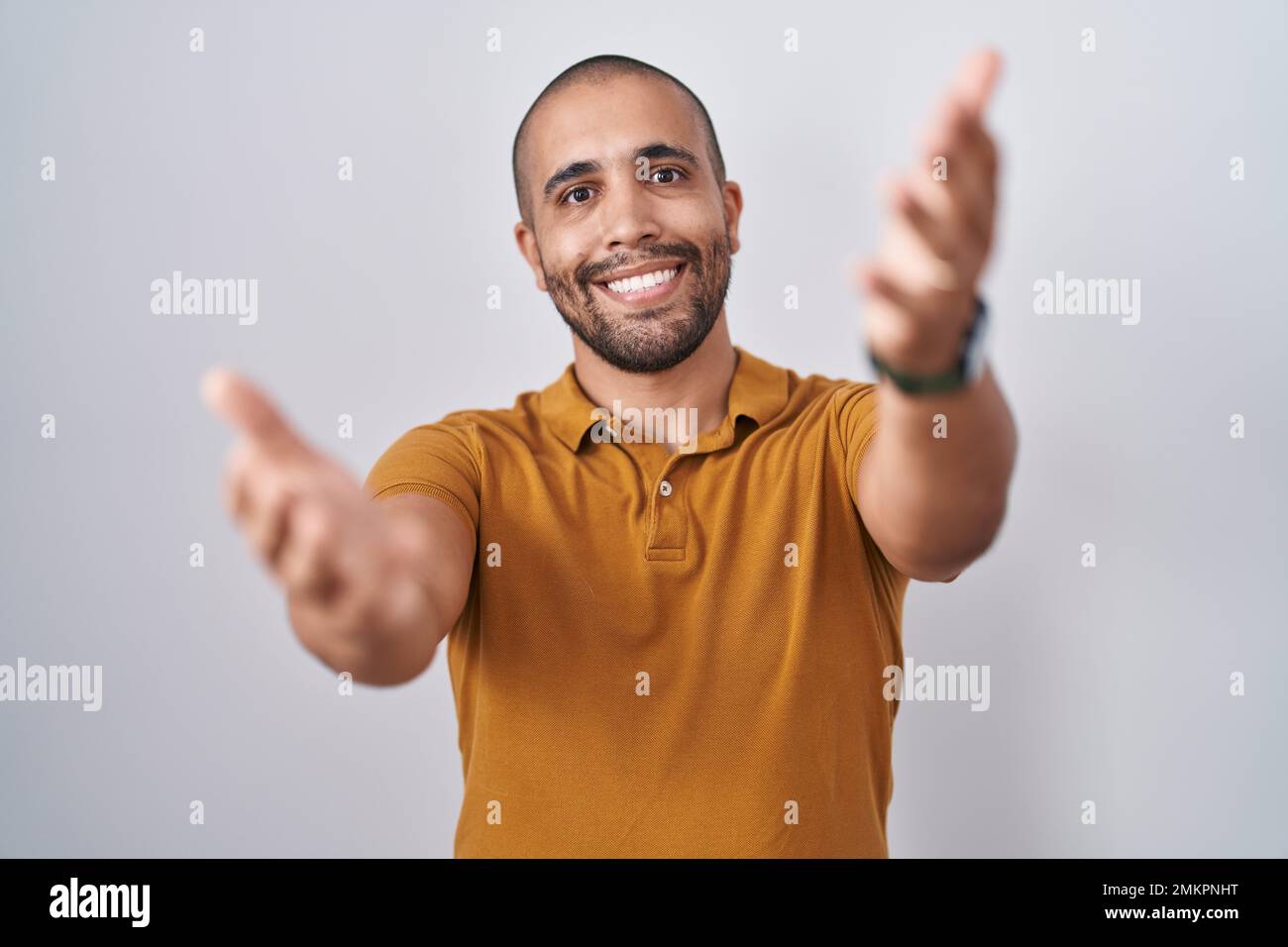 Hispanic man with beard standing over white background looking at the ...