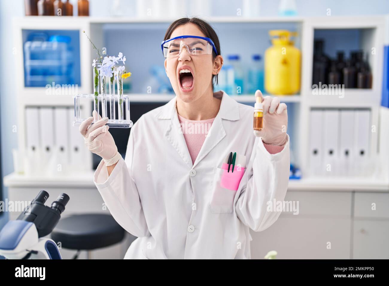 Young brunette woman working at scientist laboratory angry and mad ...