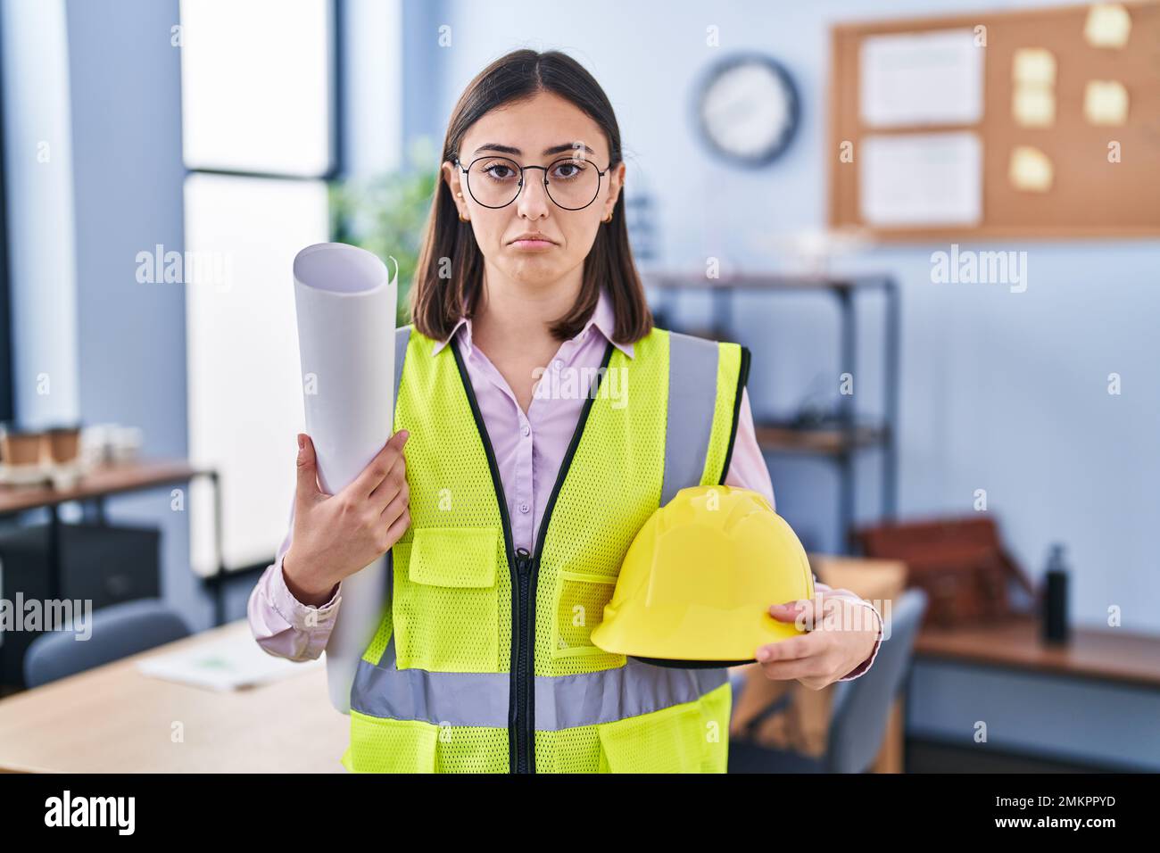 Hispanic girl architect holding build project blueprints depressed and ...
