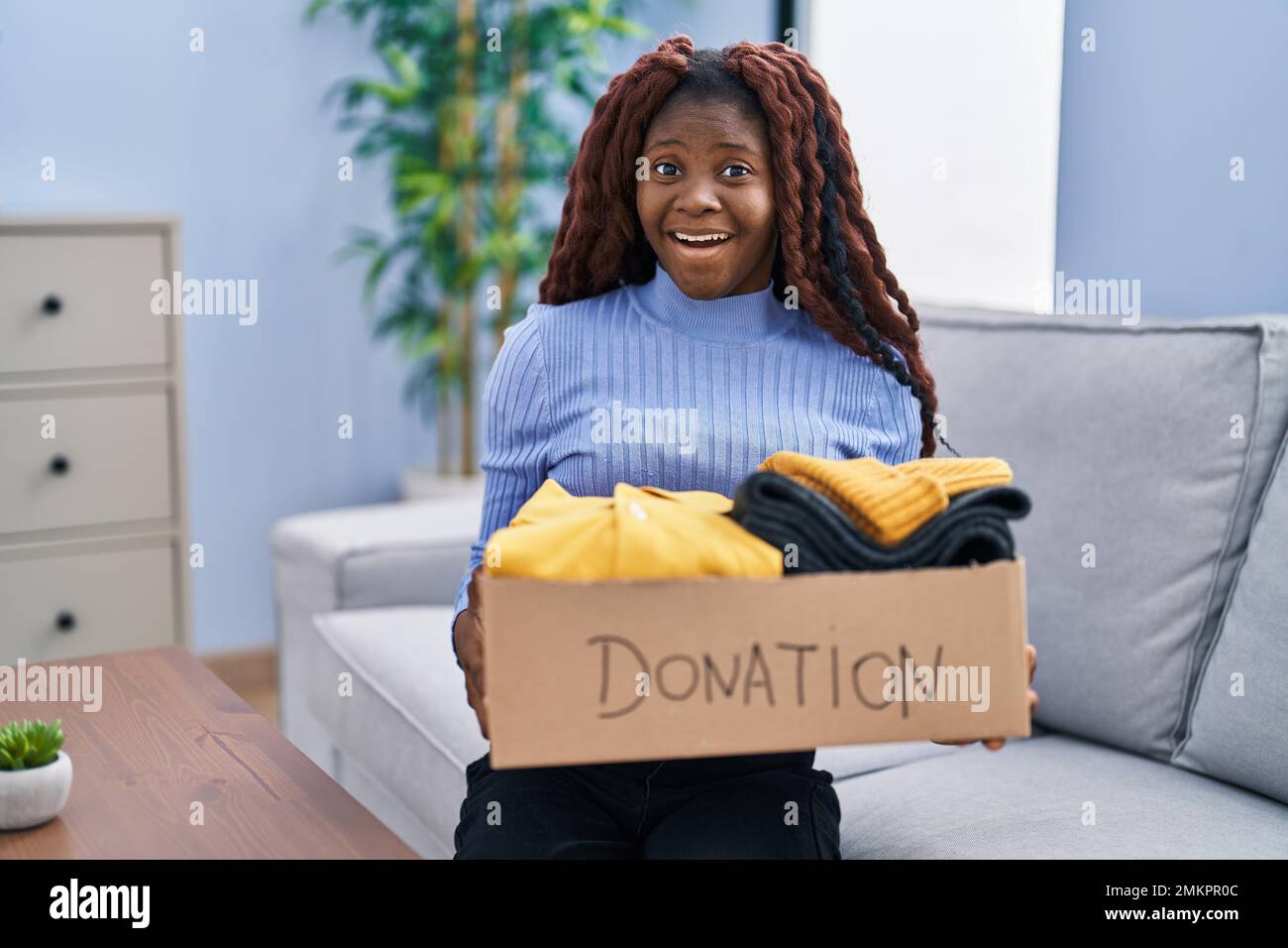 African woman holding donations box for charity celebrating crazy and ...
