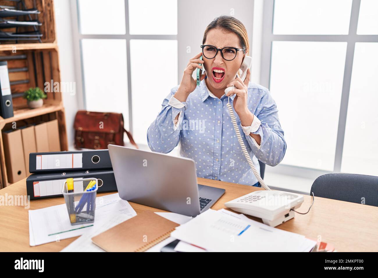 Young hispanic business woman working at the office talking on two ...