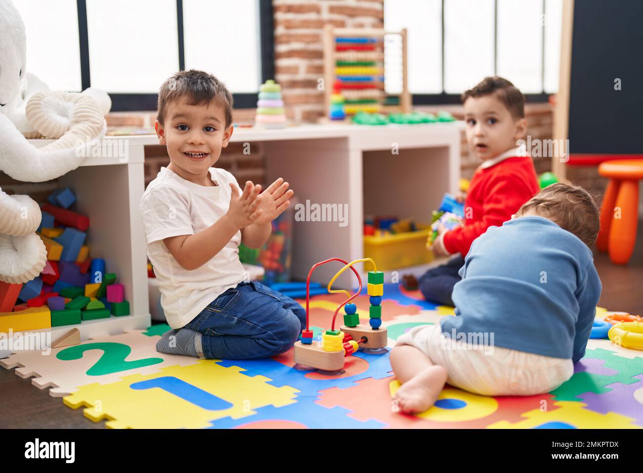 Group of kids playing with toys sitting on floor at kindergarten Stock ...