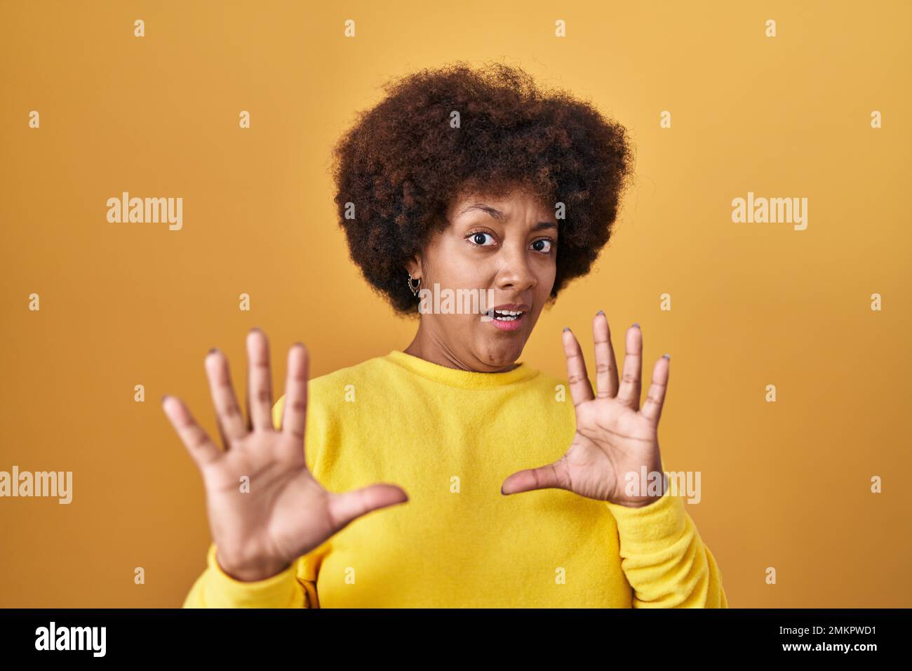 Young african american woman standing over yellow background afraid and ...