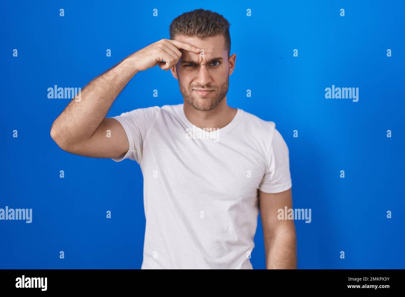 Young caucasian man standing over blue background pointing unhappy to ...