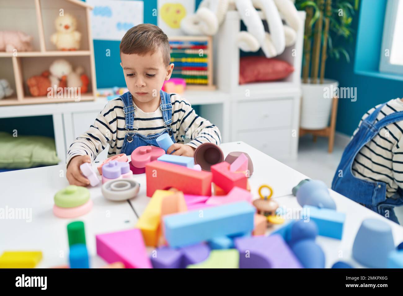 Adorable caucasian boy sitting on table playing with toys at ...