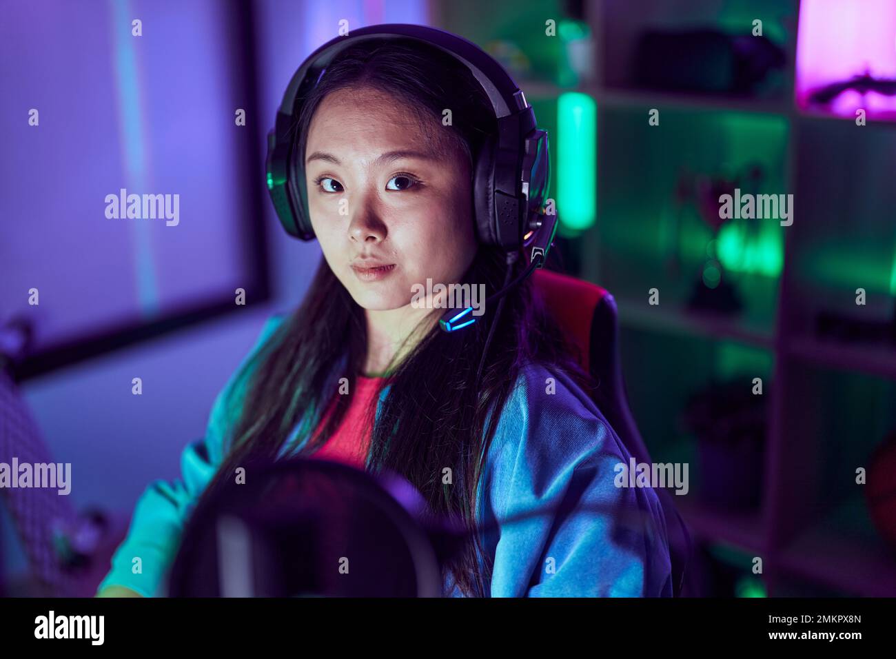 Young chinese woman streamer playing video game using computer at ...