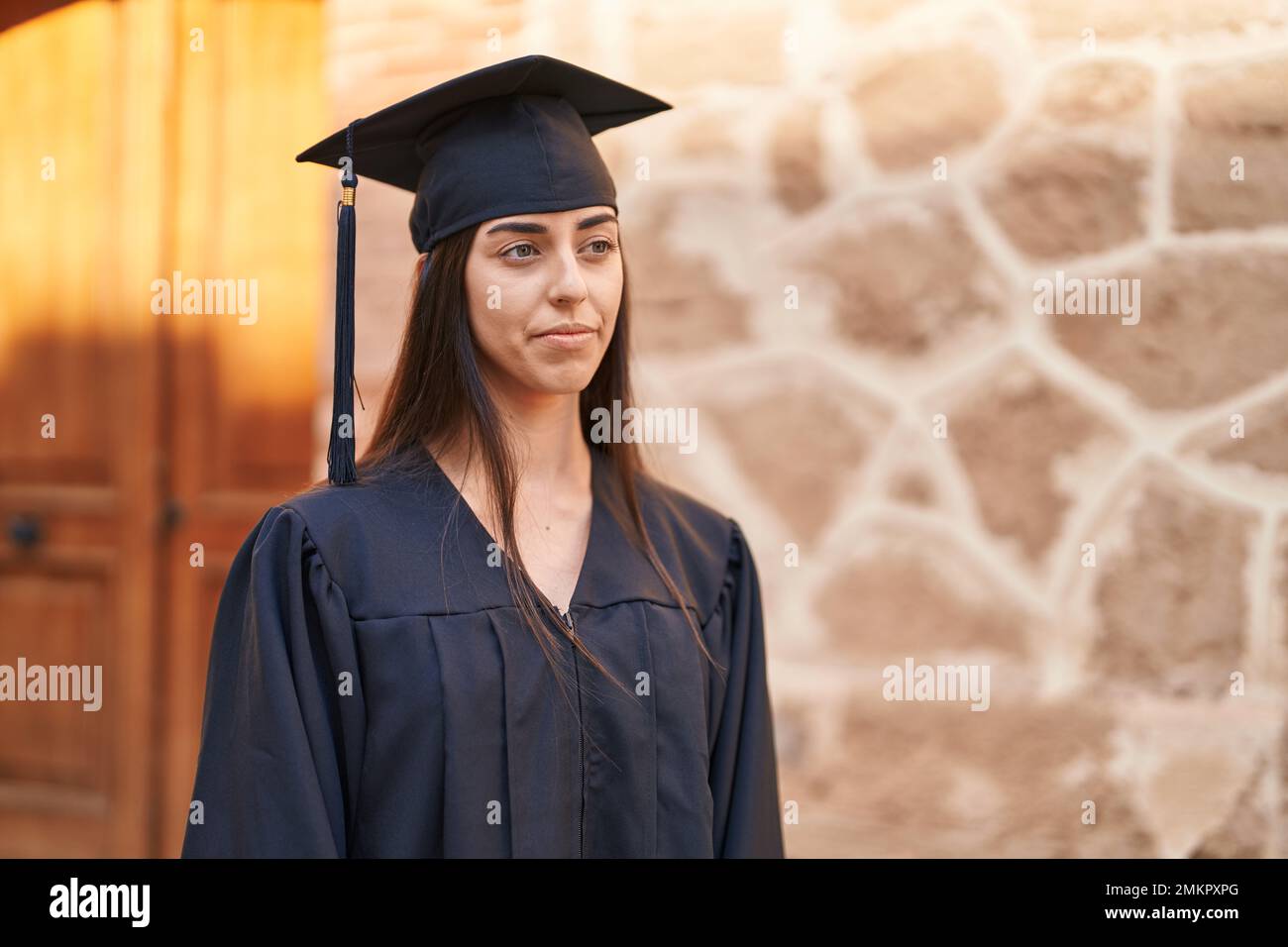 Young hispanic woman wearing graduated uniform standing with relaxed ...