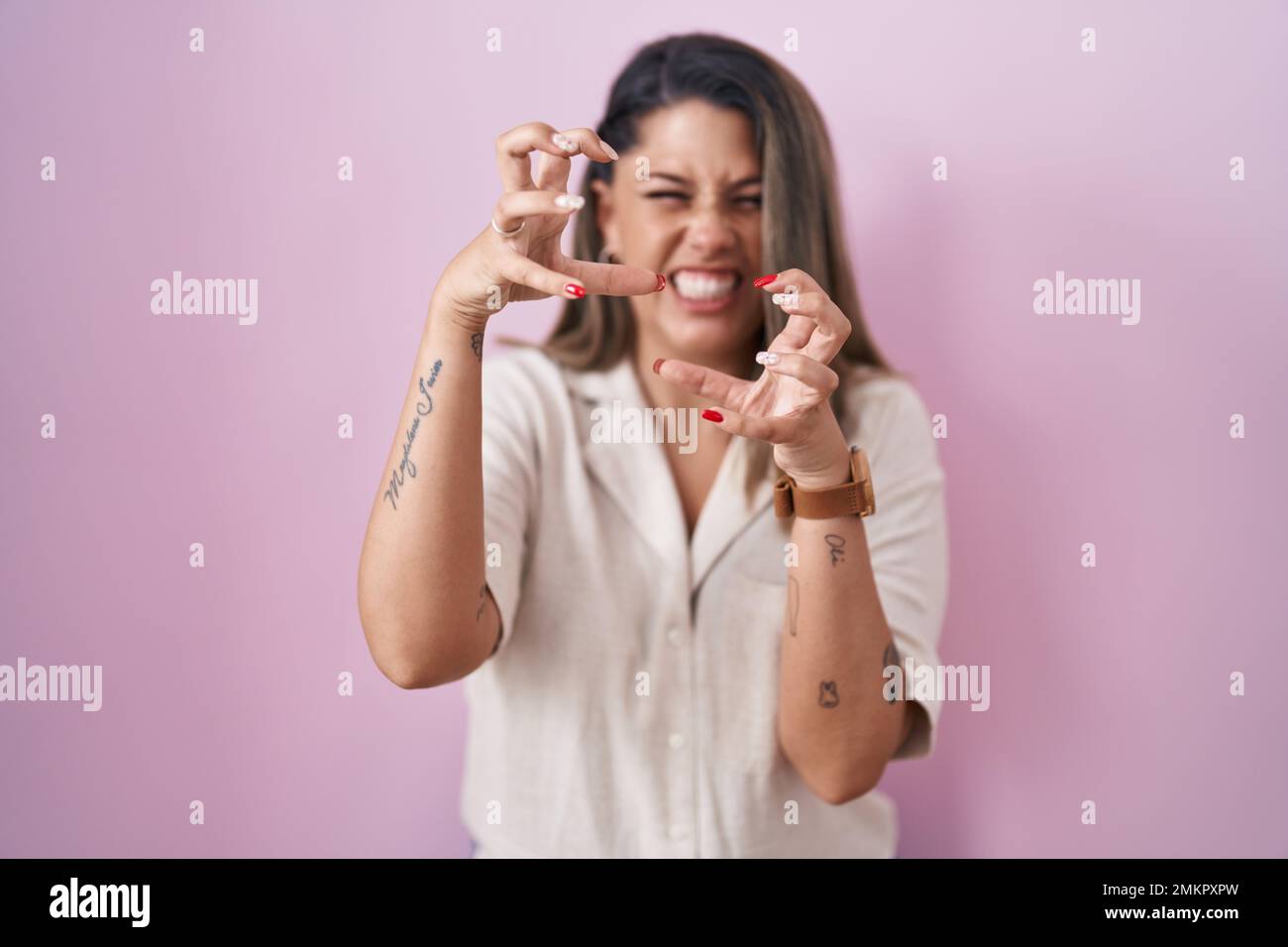 Blonde woman standing over pink background shouting frustrated with ...