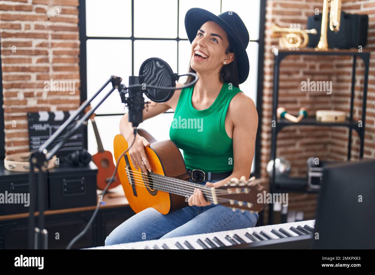 Young hispanic woman musician singing song playing classical guitar at music studio Stock Photo ...