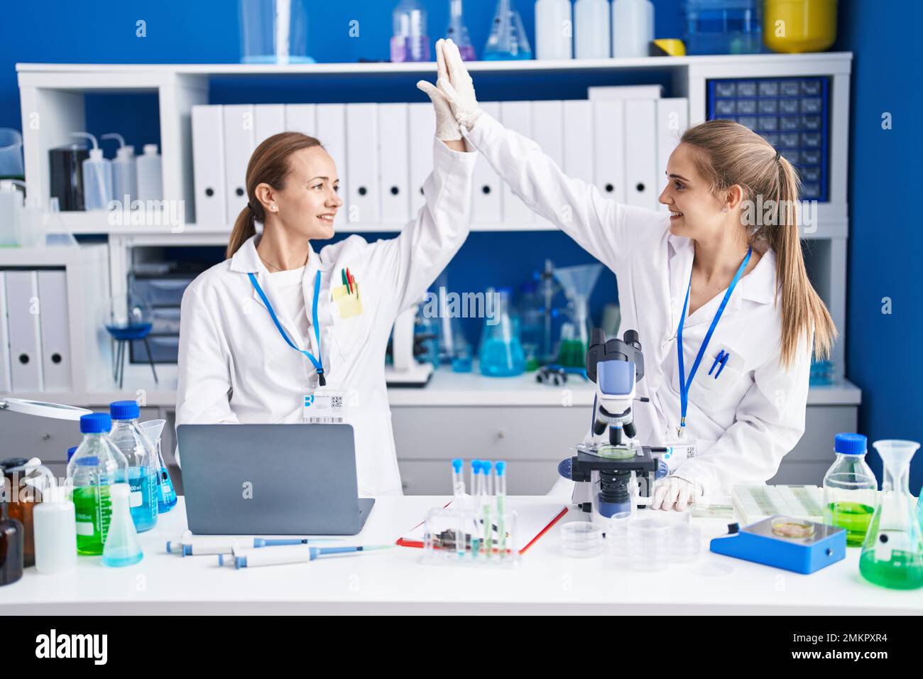 Two women scientists high five with hands raised up at laboratory Stock ...