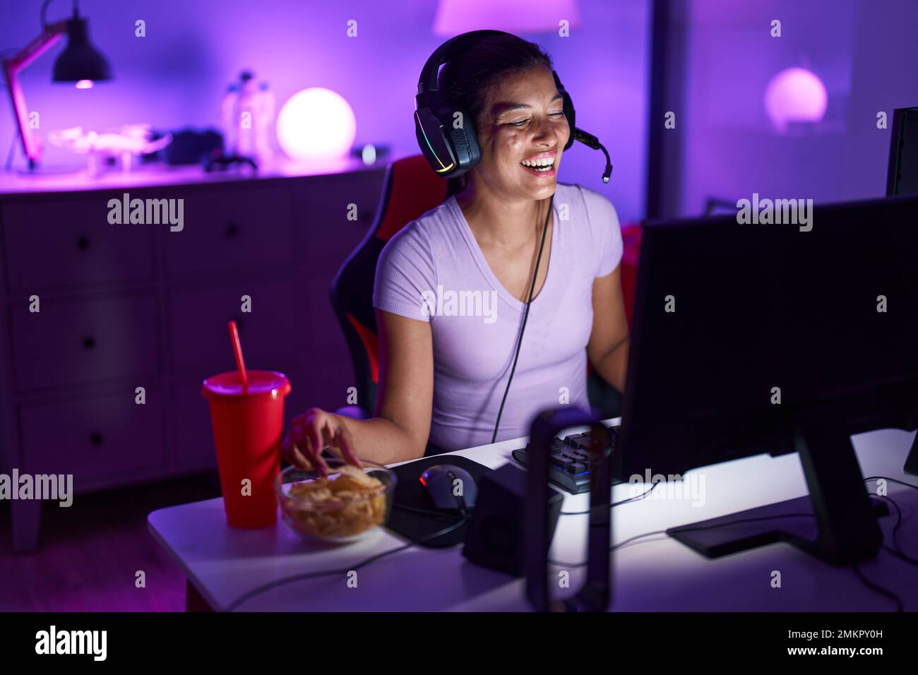 Young beautiful hispanic woman streamer playing video game at gaming ...