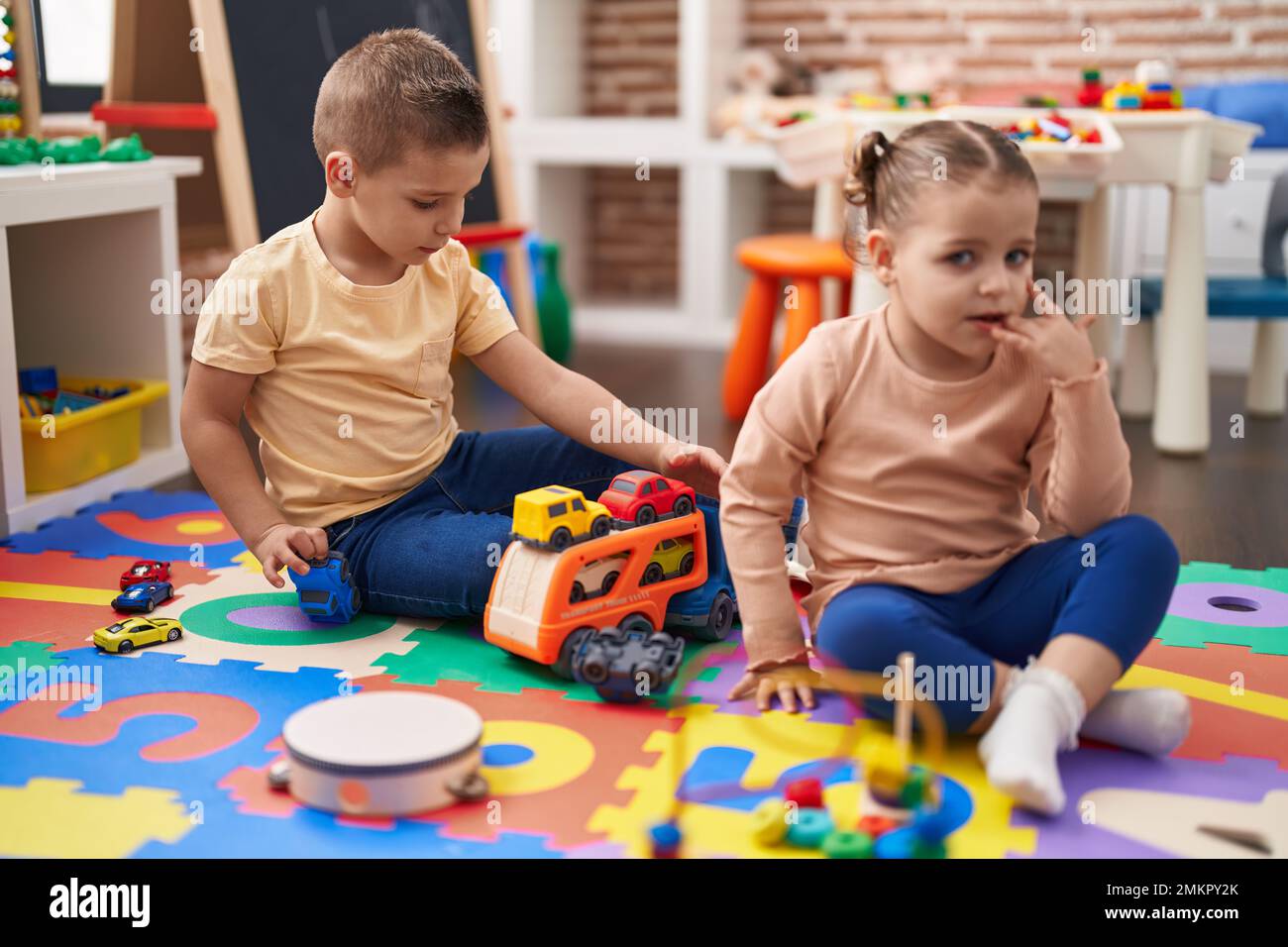 Two kids playing with cars toy sitting on floor at kindergarten Stock ...