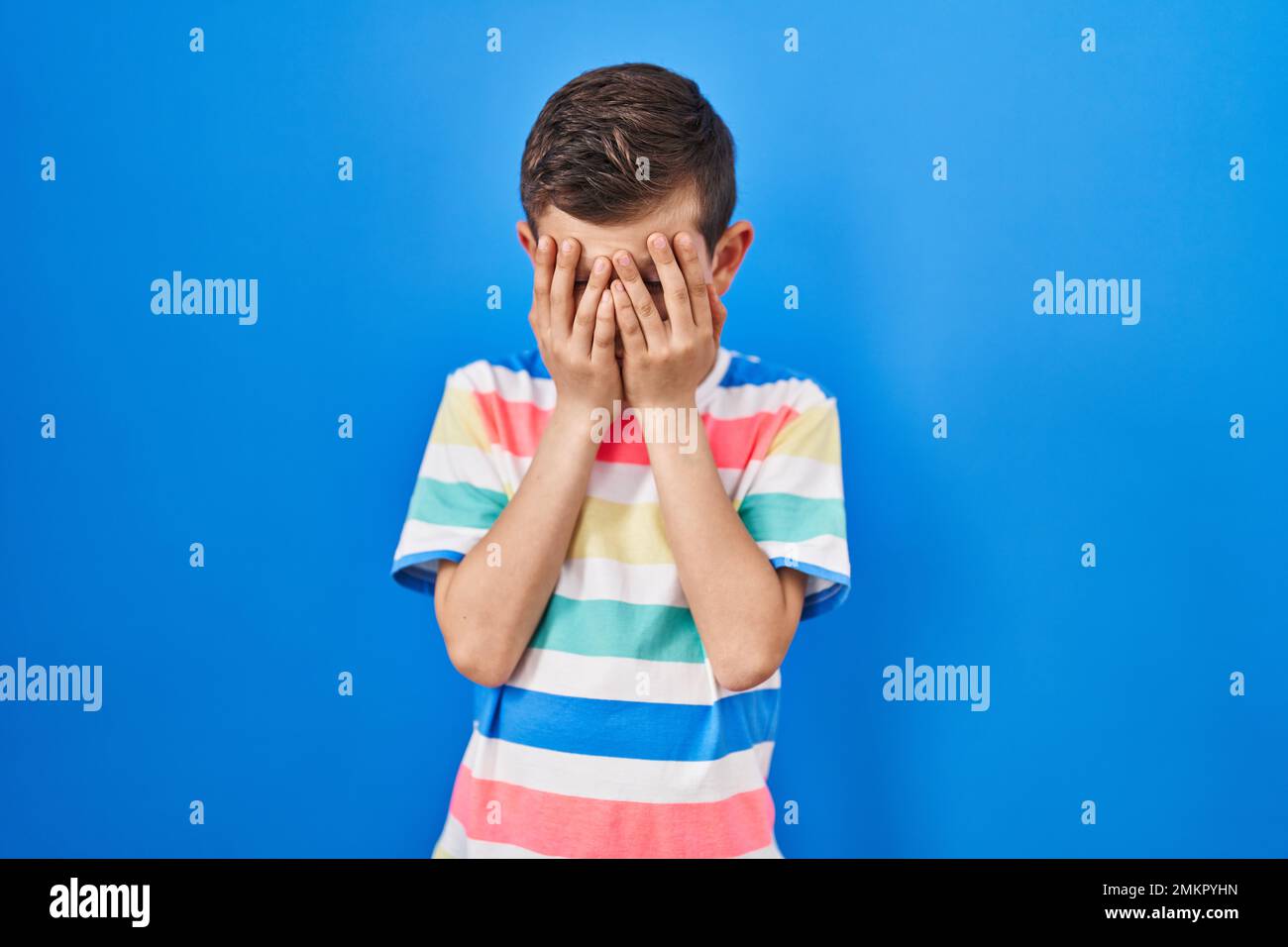 Young caucasian kid standing over blue background with sad expression ...